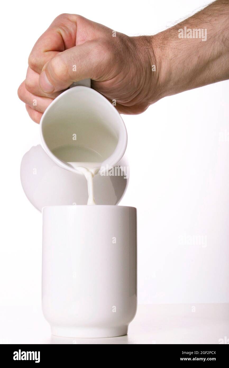 pouring milk from a pitcher into a cup Stock Photo - Alamy