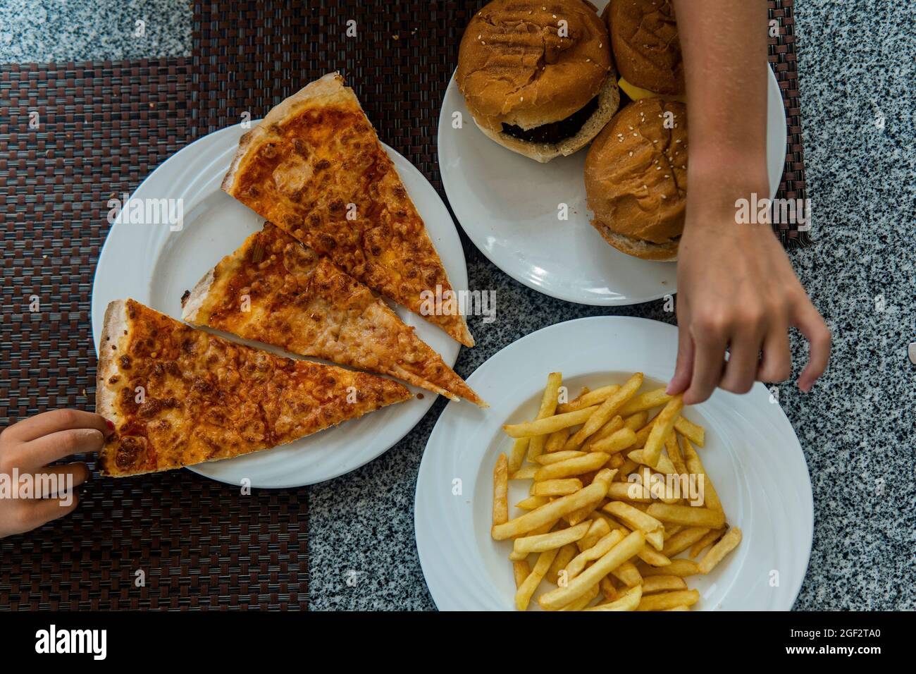 children's hands to take fast food on the table. Pizza, hamburger ...