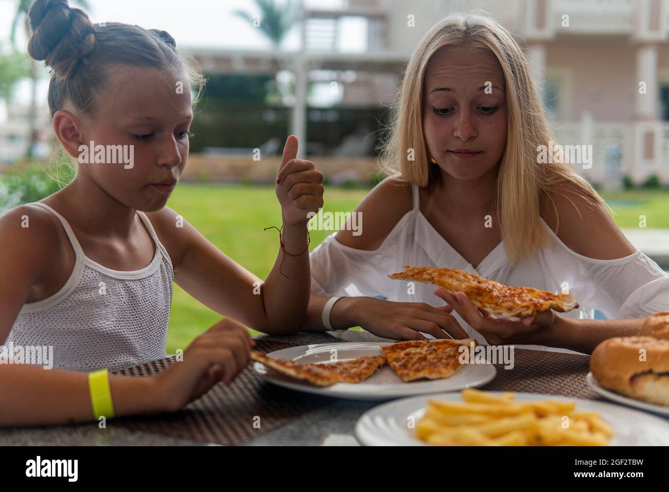 two teenage girls eating fast food and laughing Stock Photo - Alamy