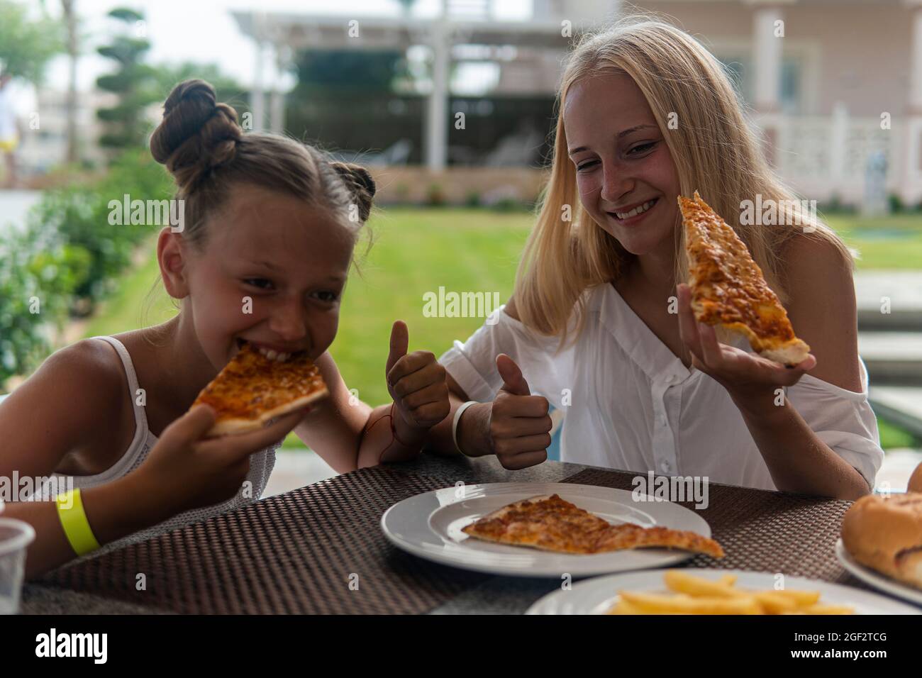 two teenage girls eating fast food and laughing Stock Photo - Alamy