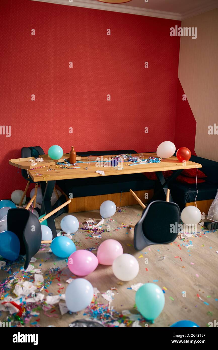 After party chaos, messy in livving room at home, table with pizza and ...