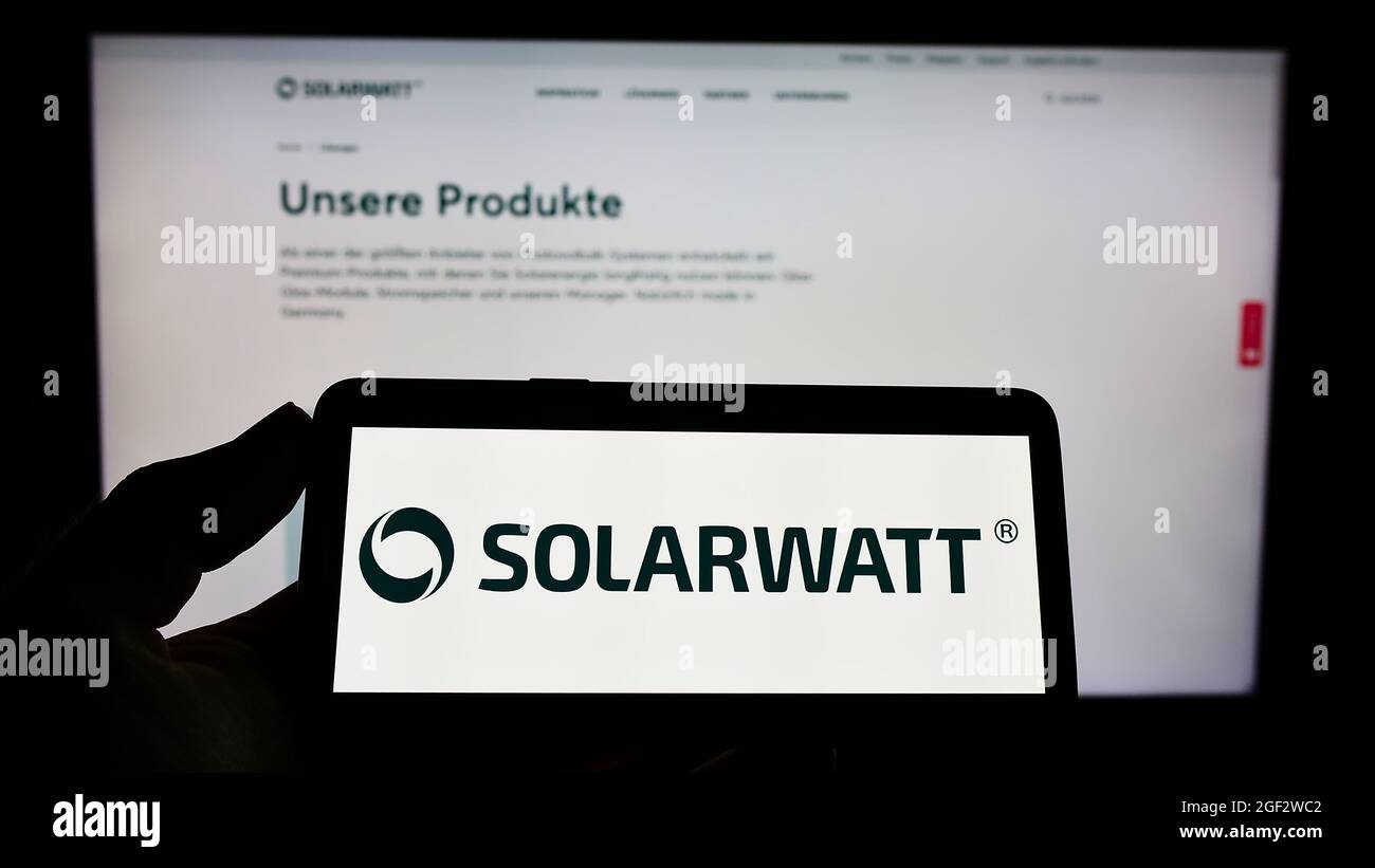 Person holding mobile phone with logo of German solar energy company ...