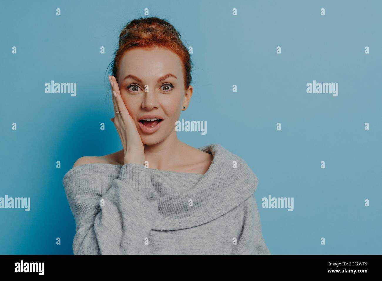 Surprised amazed red haired woman with impressed face expression ...