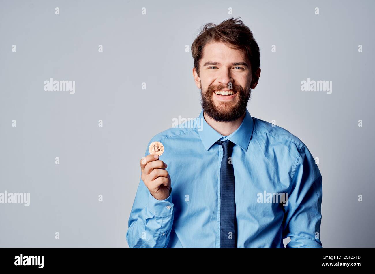 Cheerful business man holding Bitcoin coin in hands of virtual money ...
