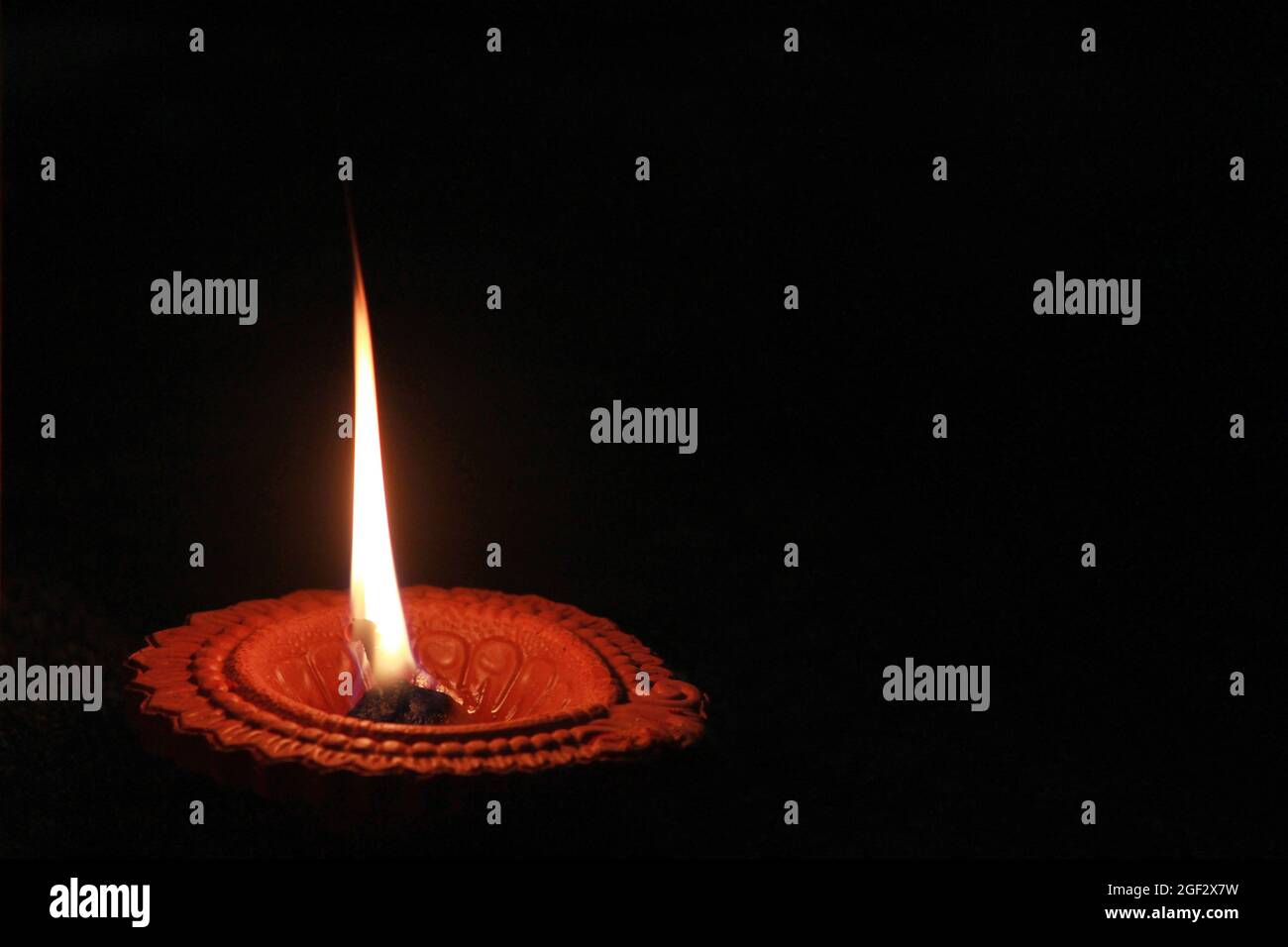A lit Diya or Traditonal oil Lamp which is lit at Diwali gainast a ...