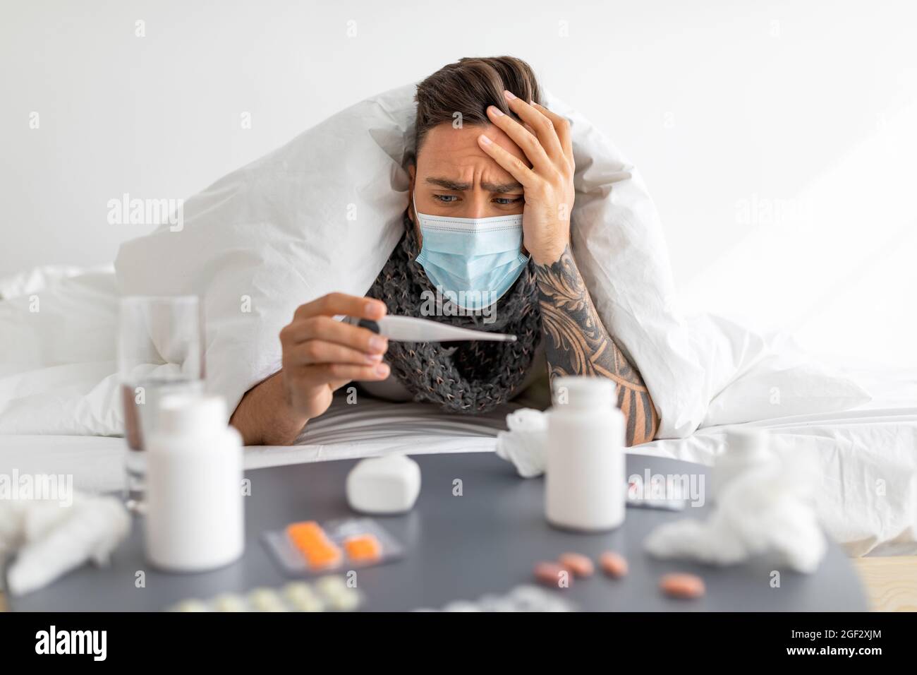 Shocked sick guy in mask looking at thermometer with high temperature ...
