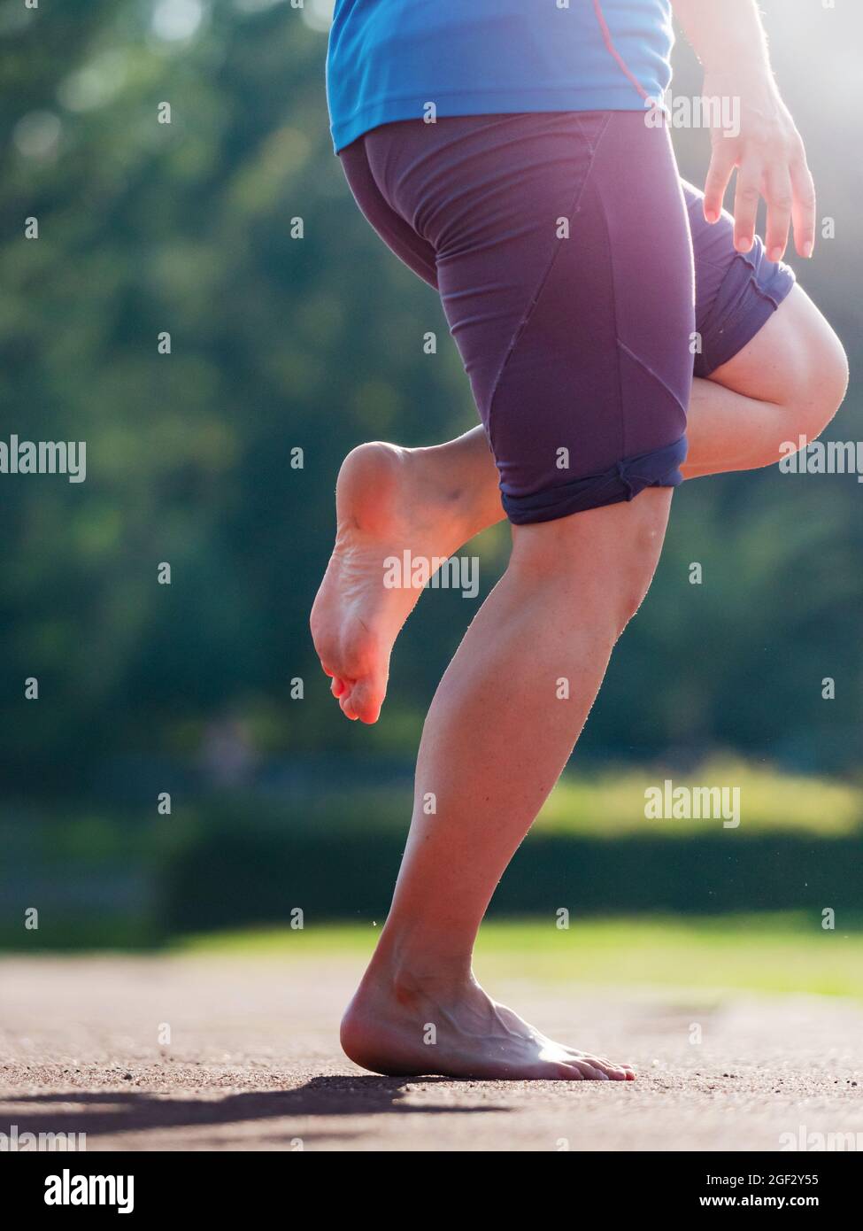 Forthy yeas old woman stretching legs before run during sunny morning ...
