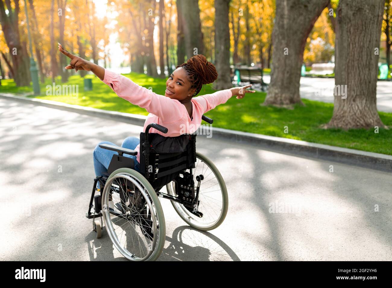 Young disabled black woman in wheelchair spreading arms, making victory ...