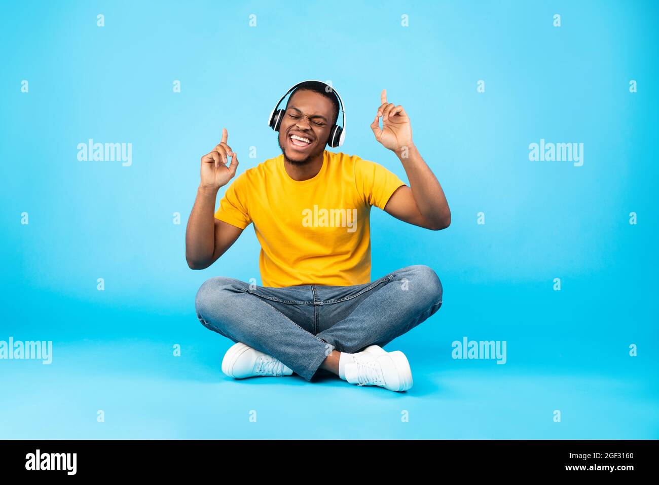 African Man Listening Music And Singing Wearing Headphones, Blue Background Stock Photo - Alamy