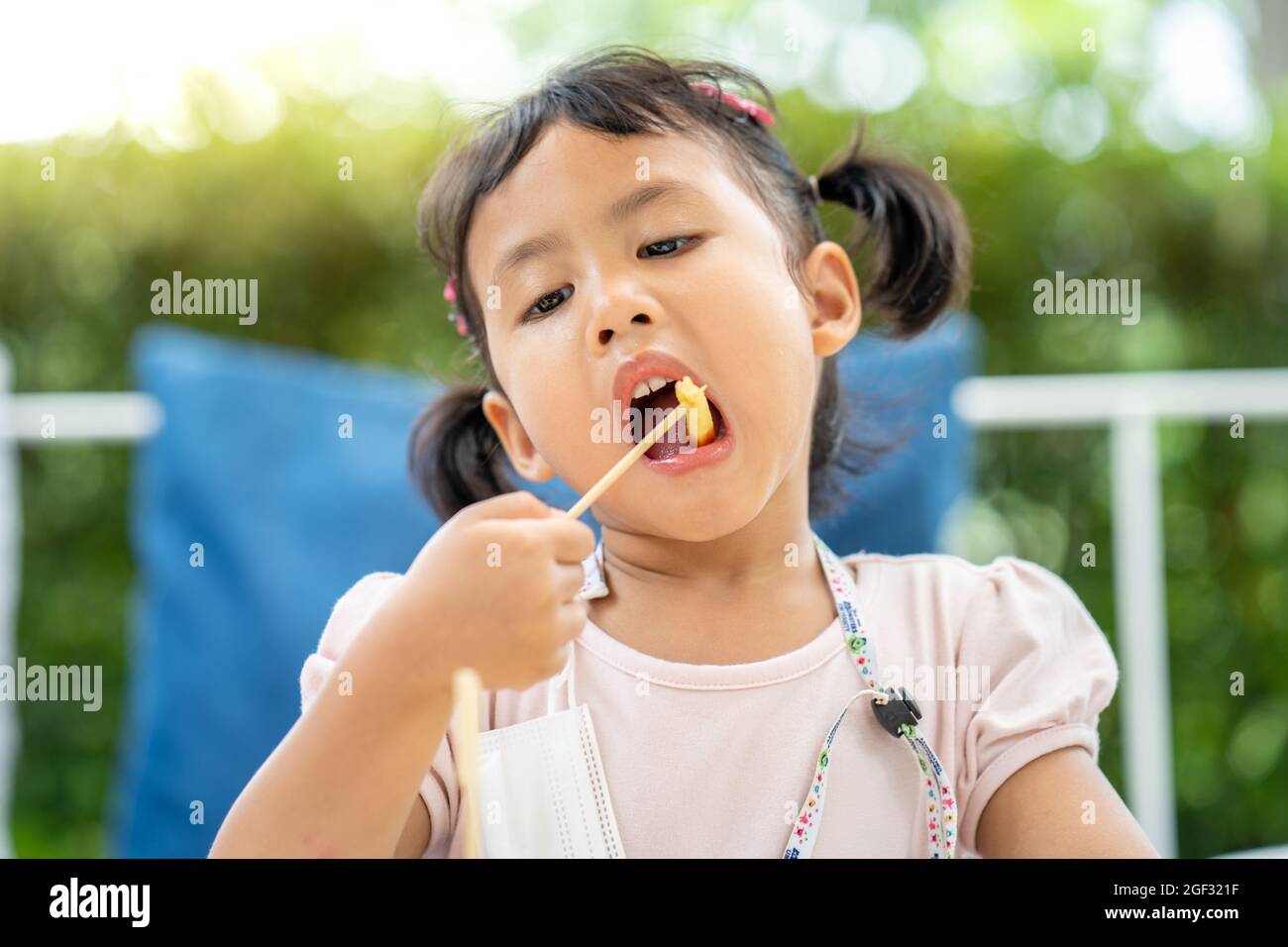 Southeast Asian female kid eating potato fries outdoors Stock Photo - Alamy