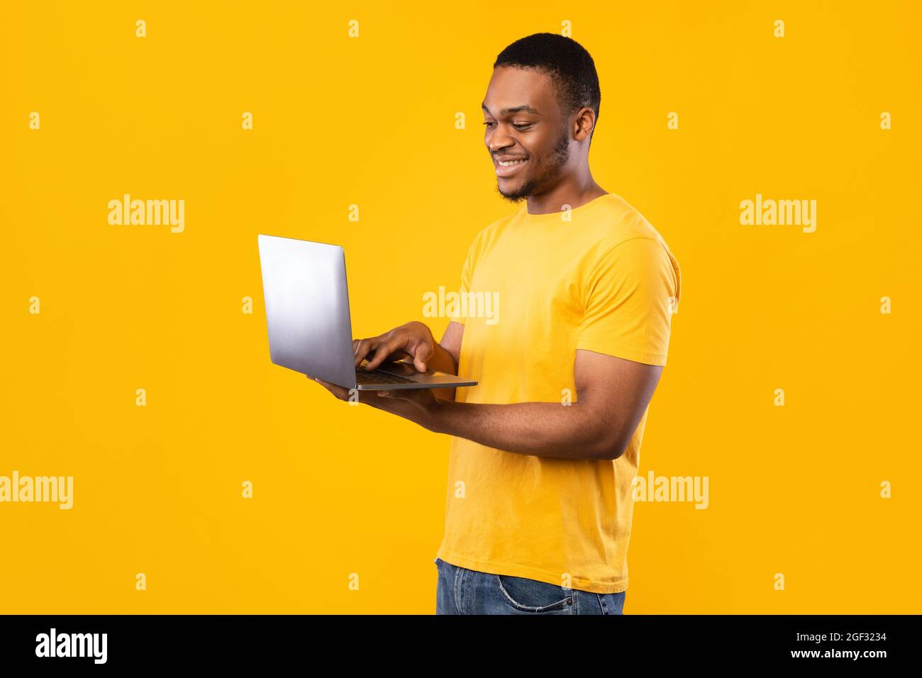 Happy African American Freelancer Man Using Laptop Over Yellow ...
