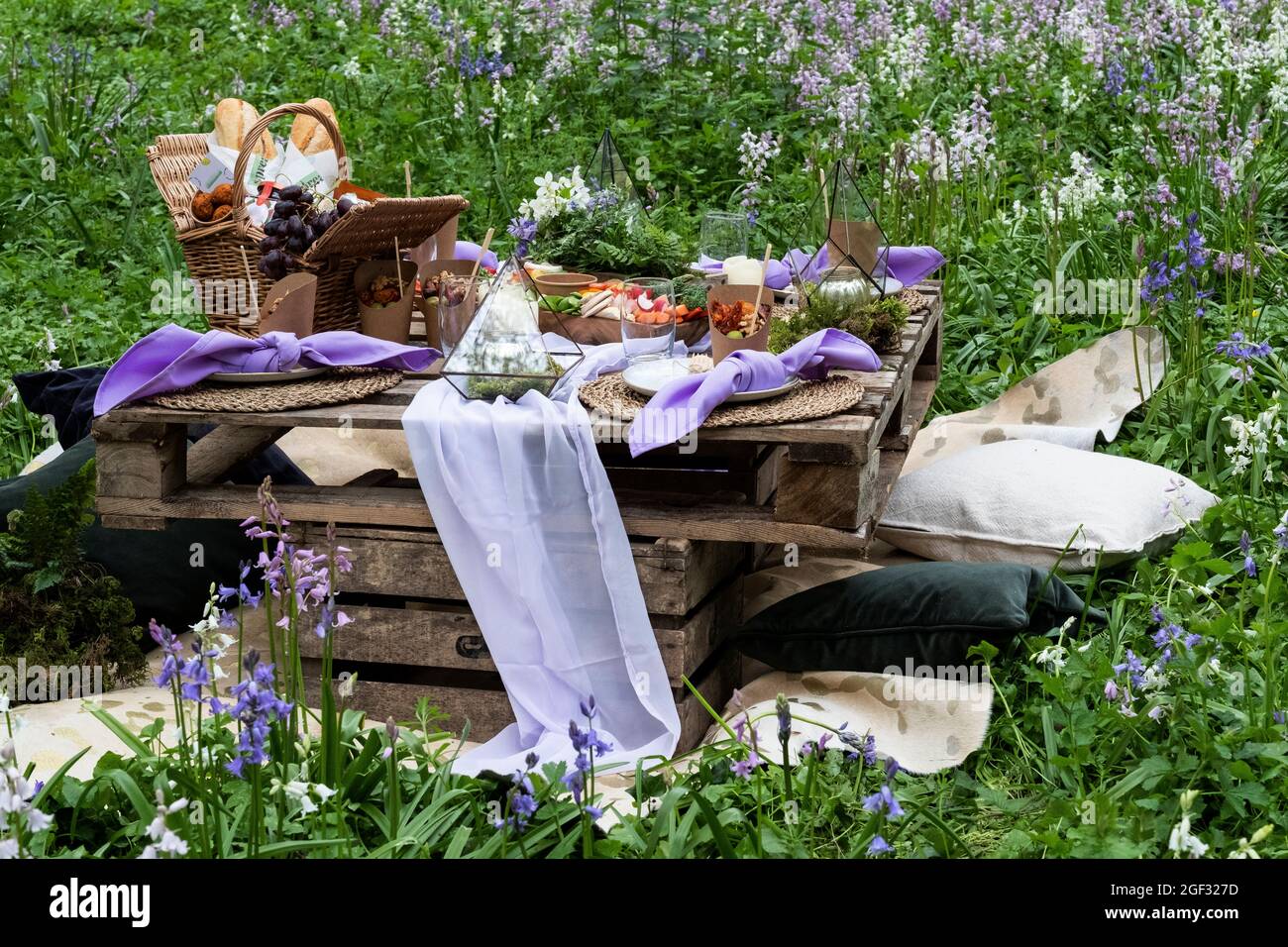Rustic picnic table with food in a spring meadow for a woodland naming ...