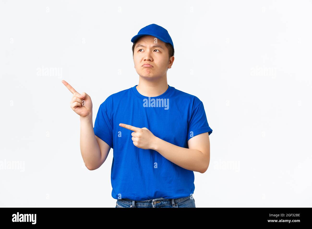 Skeptical and disappointed asian courier in blue uniform complaining ...