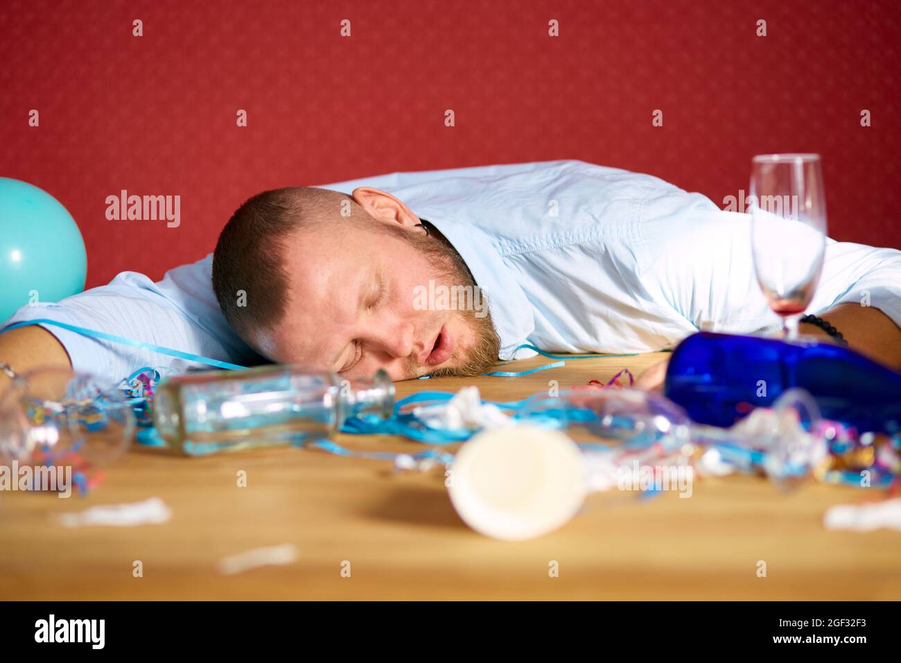 Bearded man sleeping at table in messy room after bachelor party, tired ...