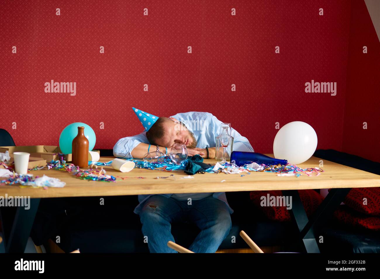 Man sleeping at table with blue cap in messy room after birthday party ...