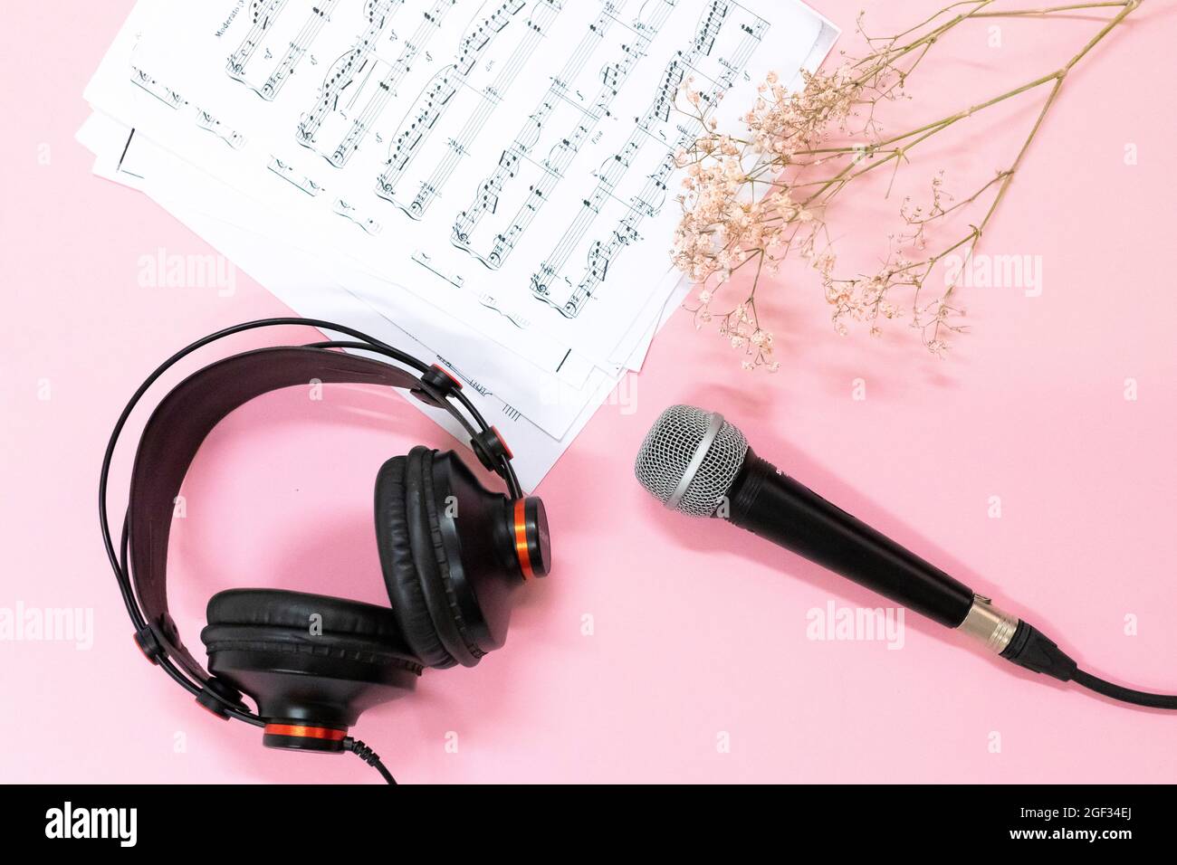 Top view of flat lay of music notes, microphone and headphones on pink ...