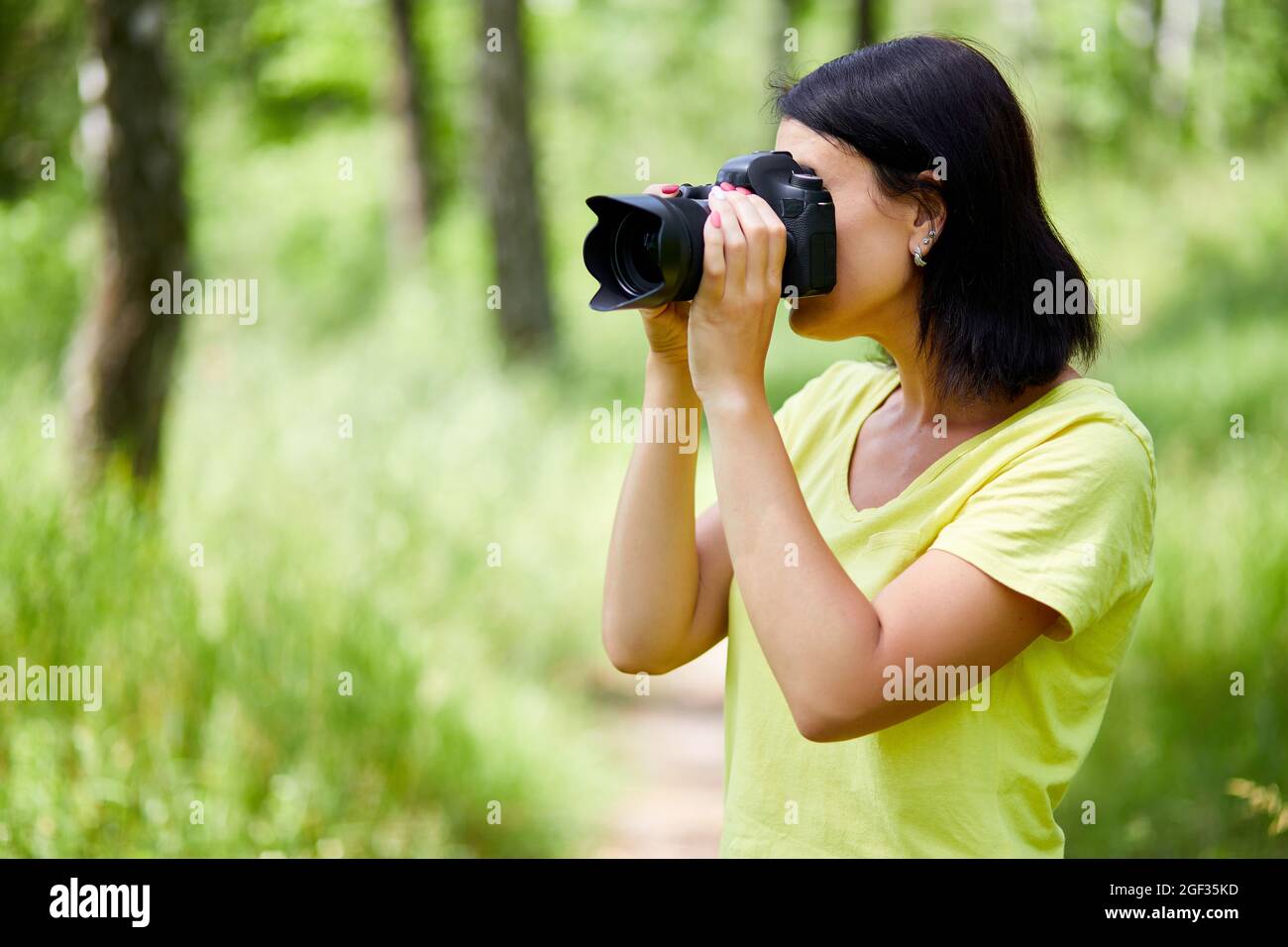Portrait of a woman photographer covering her face with the camera ...