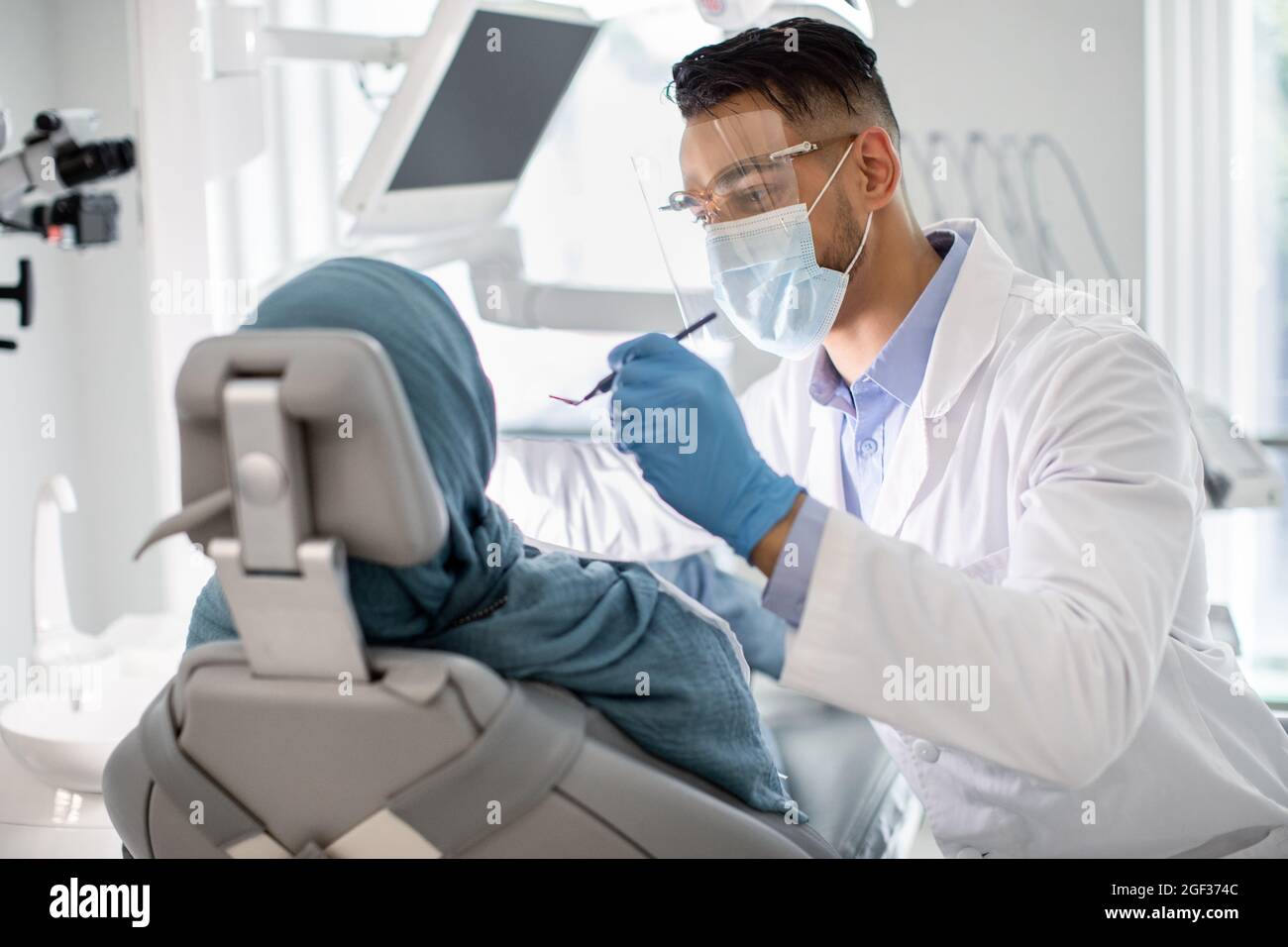 Middle-Eastern Male Dentist In Medical Mask And Face Shield Checking ...