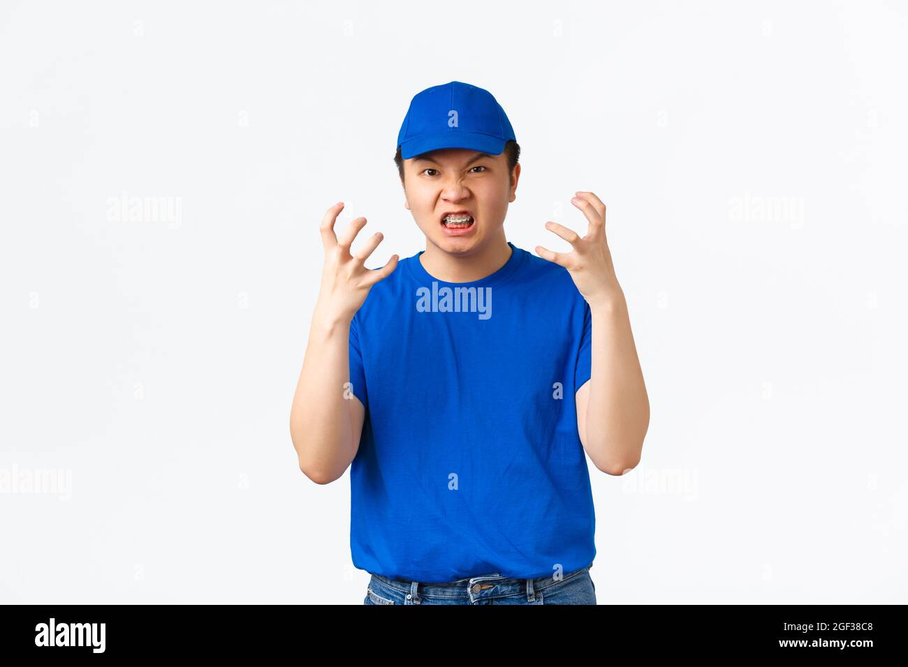Pissed-off and angry asian delivery man in blue uniform shaking hands ...