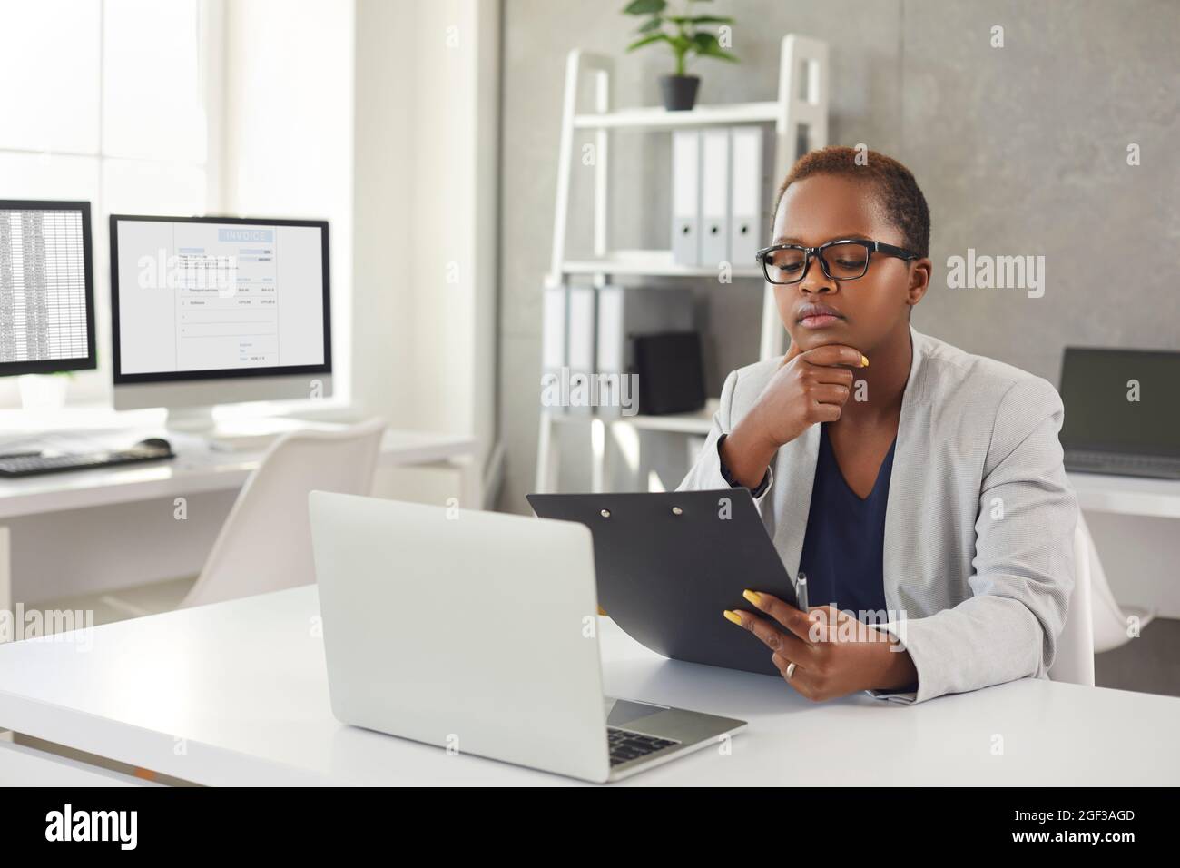 Black woman sitting at her desk in office, reading business documents ...
