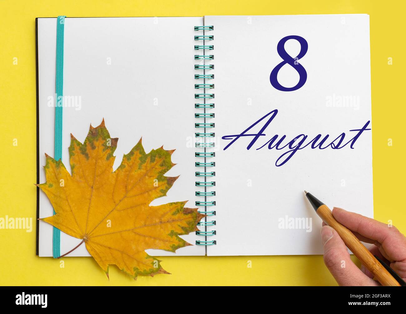 8th day of august. Hand writing the date 8 august in an open notebook ...