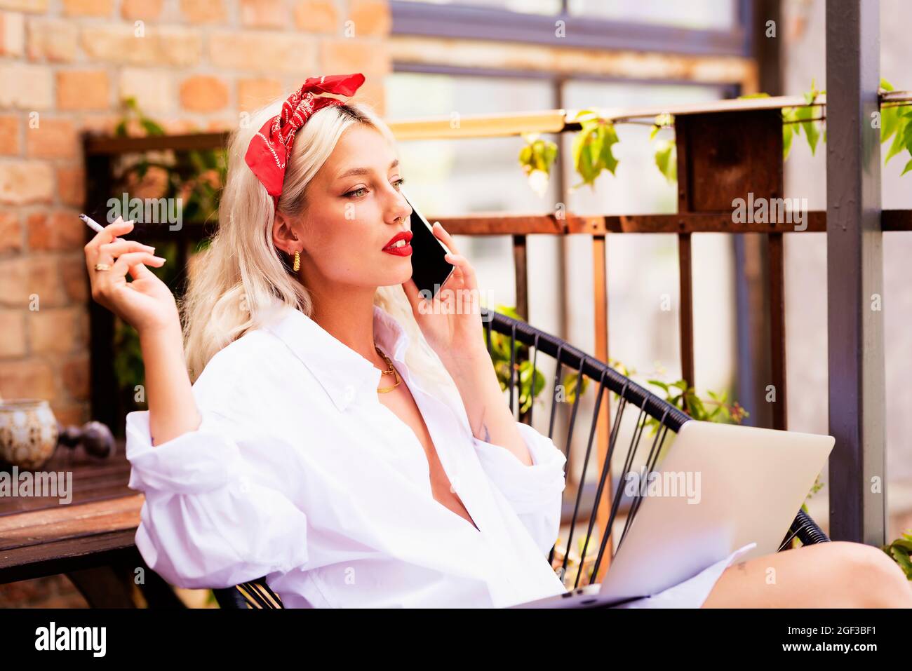 Attractive girl smoking cigarette and having phone call while working ...