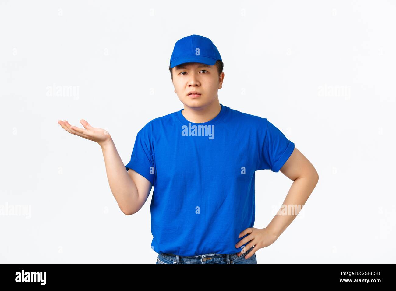 Confused and upset asian delivery man in blue uniform pointing hand ...
