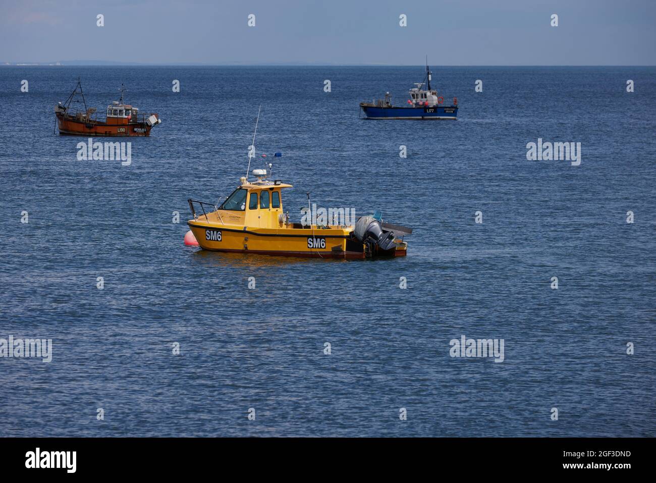 Small local fishing boats seen offshore of Selsey beach, uk, in summer ...