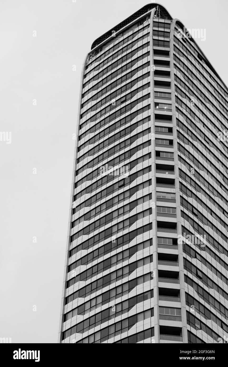 Vertical grayscale shot of a tall modern building with lots of windows ...