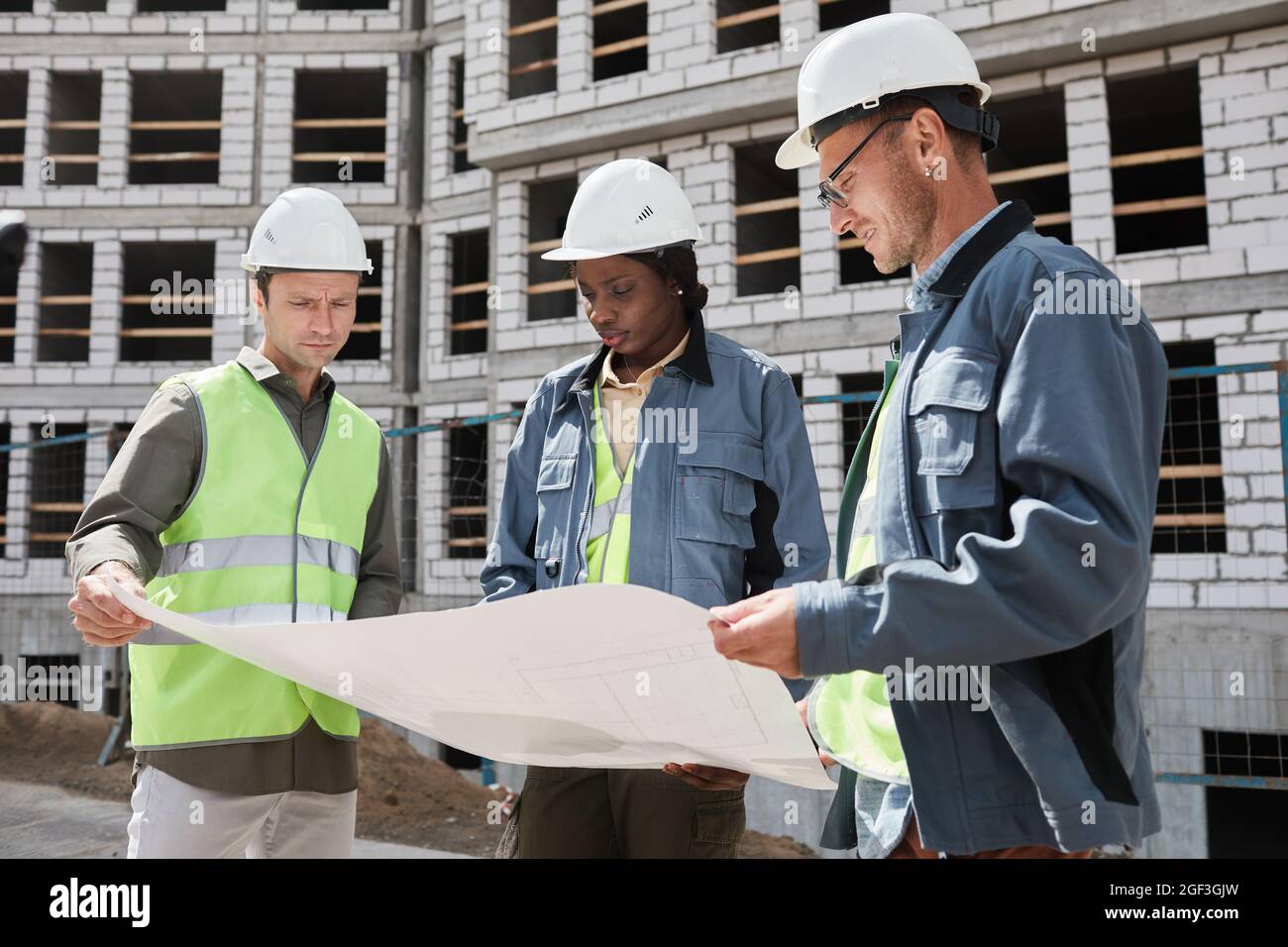 Waist up shot of diverse group of engineers discussing floor plans at ...