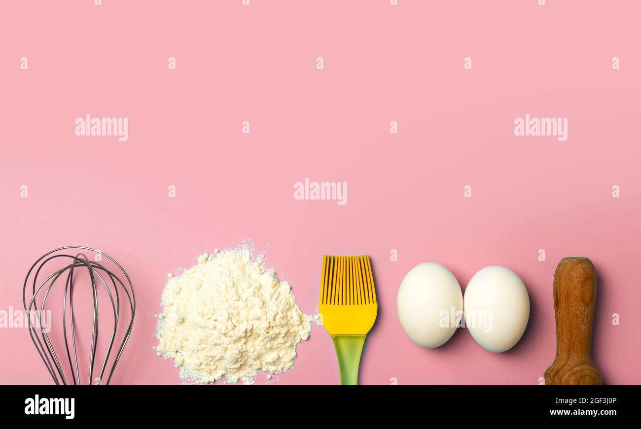 Baking and dough background. Wheat flour and kitchen items on a pink ...