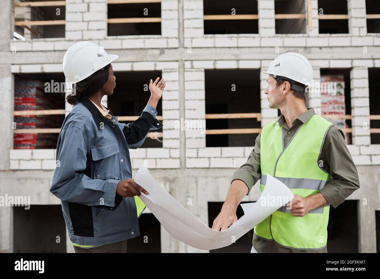 Side view portrait of two engineeers wearing hardhats at construction ...