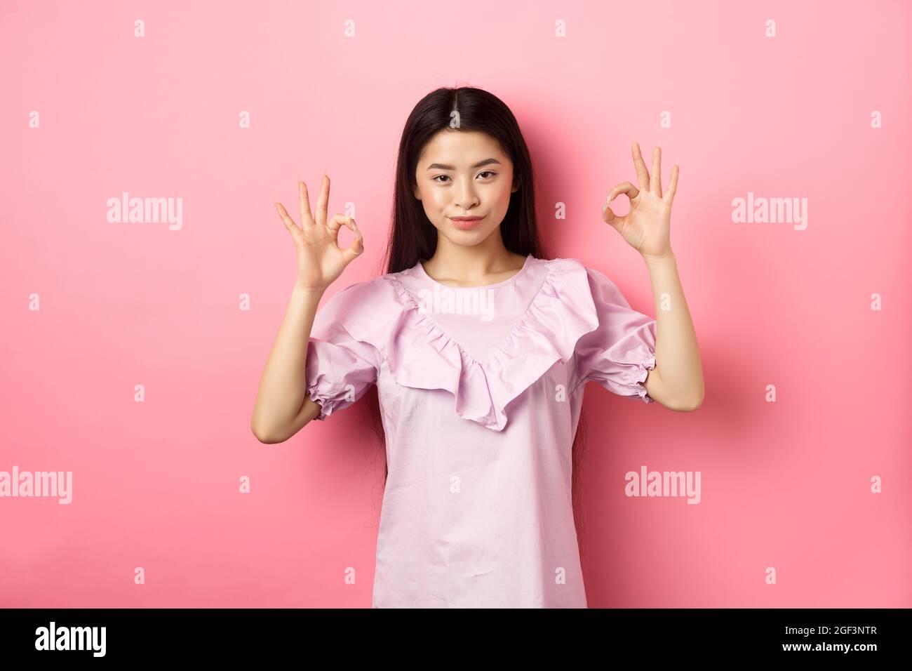 Smiling asian woman showing okay signs and looking confident, assure ...