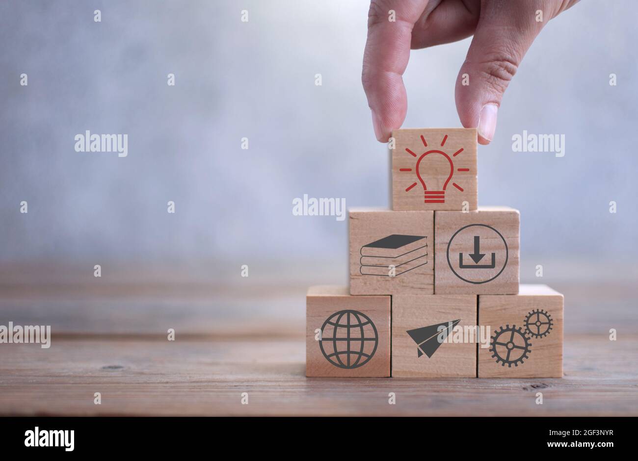 Light bulb symbol being placed on a tower of wooden building blocks ...