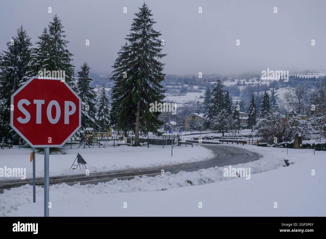 stop road sign across winter landscape in snow and road going to the ...