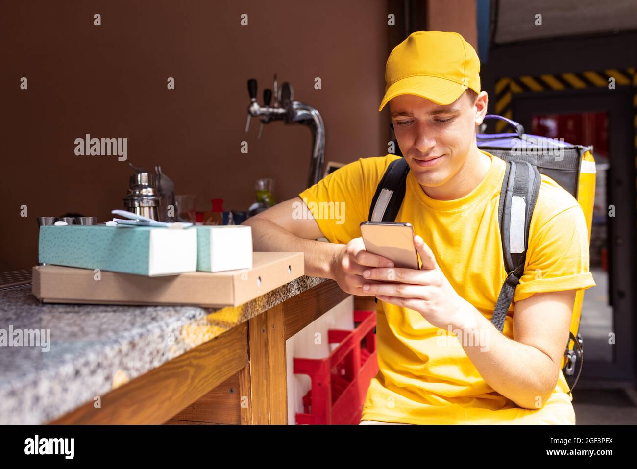 Young deliveryman in yellow uniform picking up order to clients ...