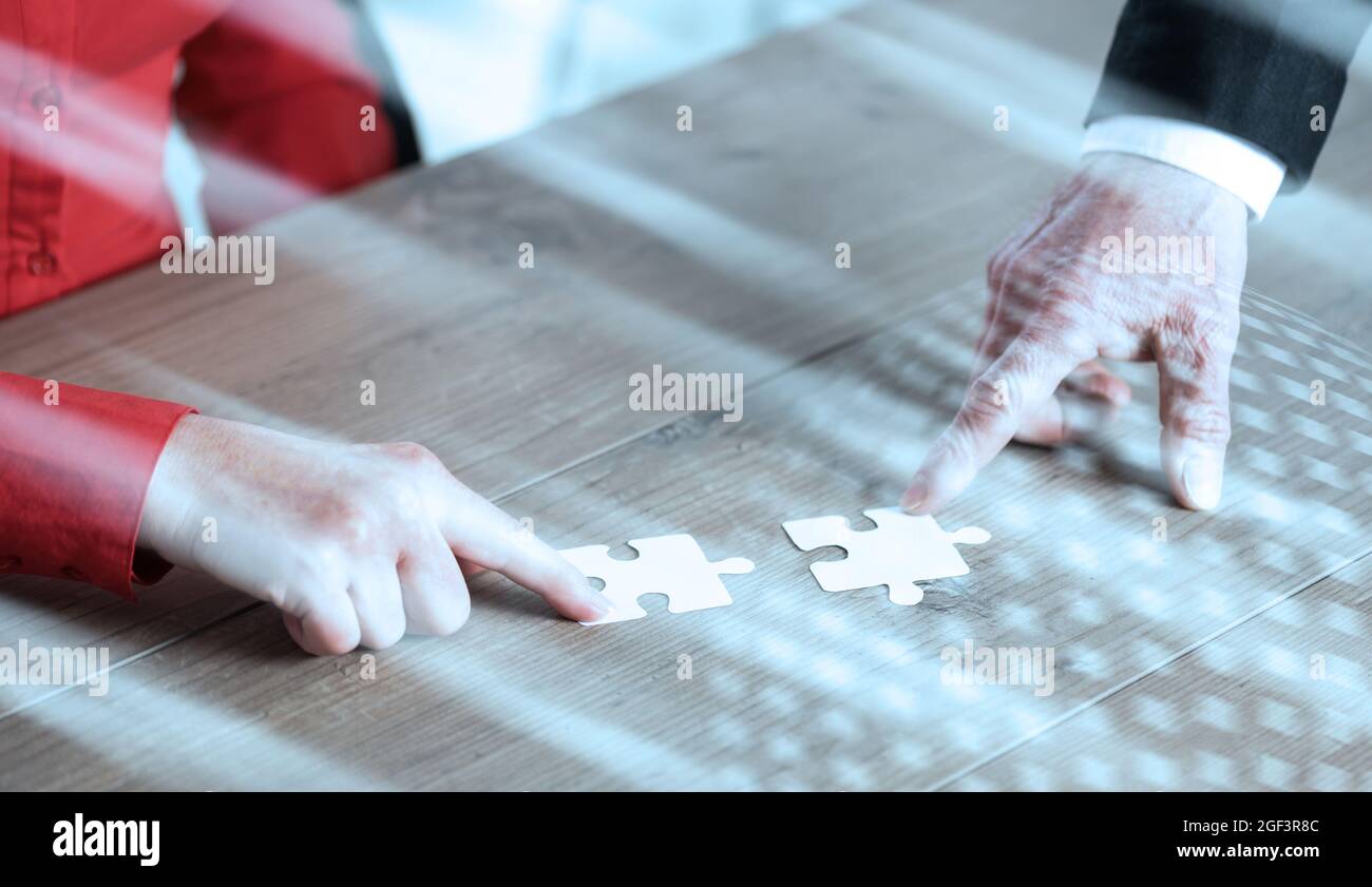 Hands joining two puzzle pieces, teamwork concept; multiple exposure ...