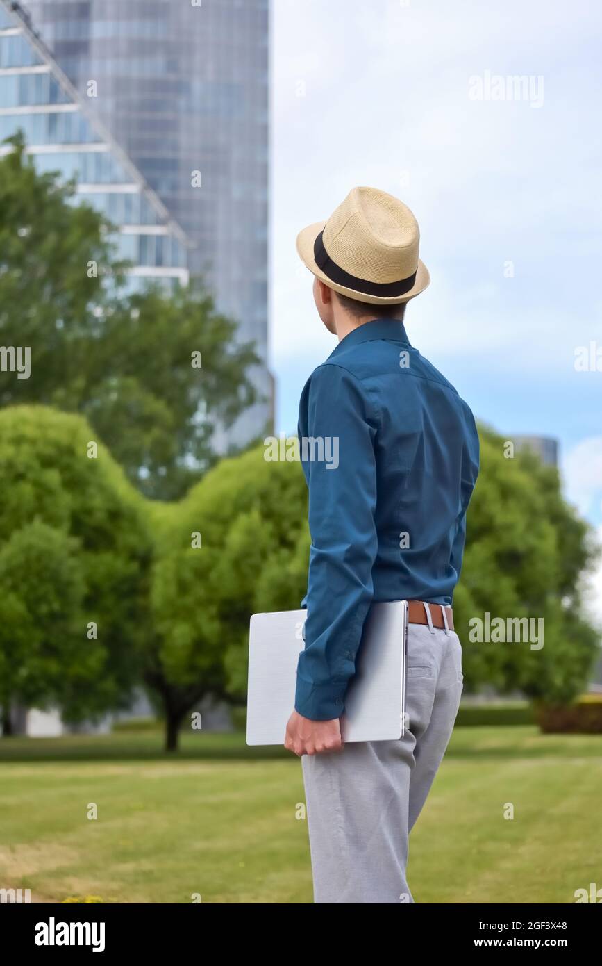 A man with a laptop in his hand stands and looks towards the office ...