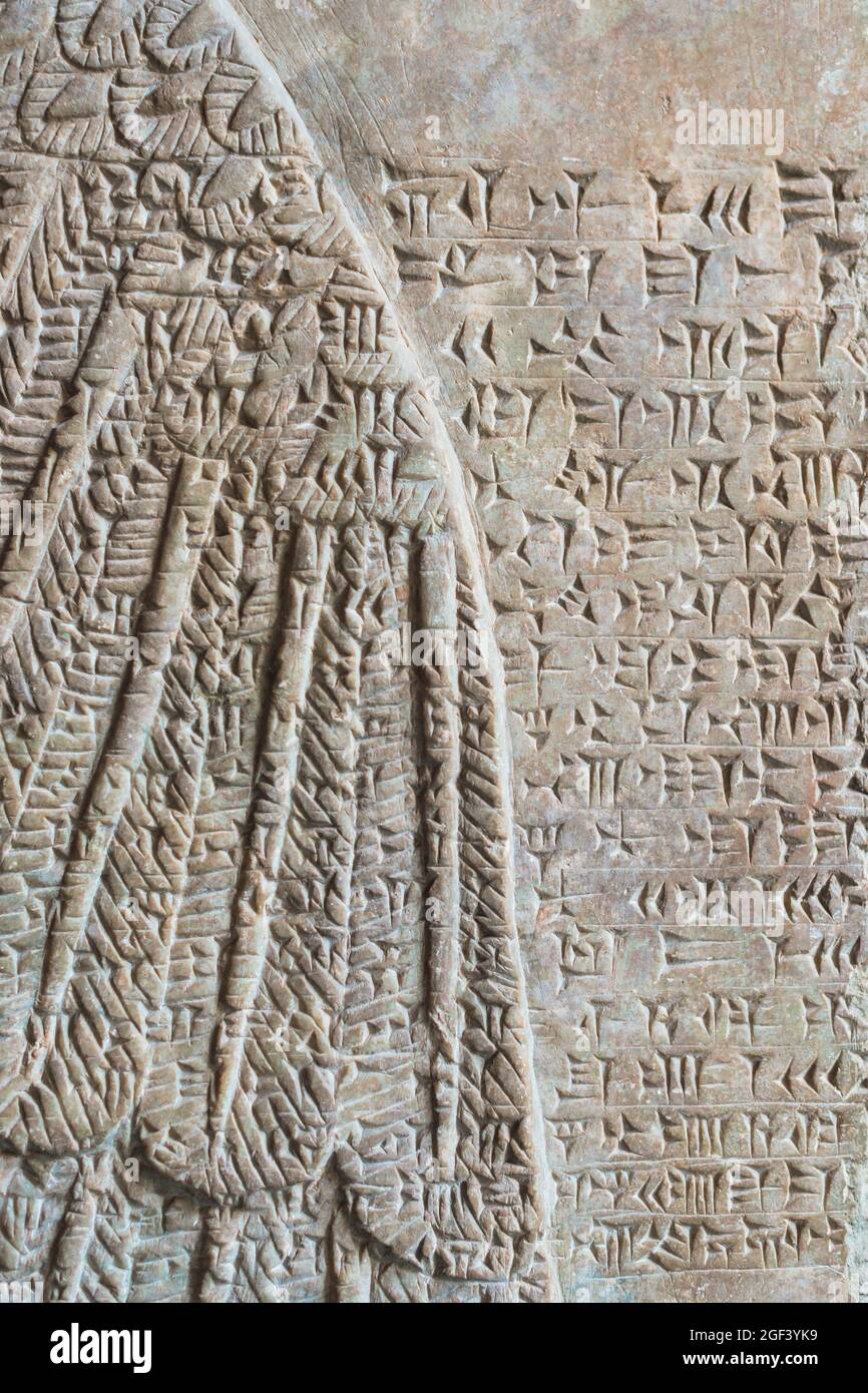 ancient Assyrian cuneiform carved on stone wall over sphinx wing relief ...