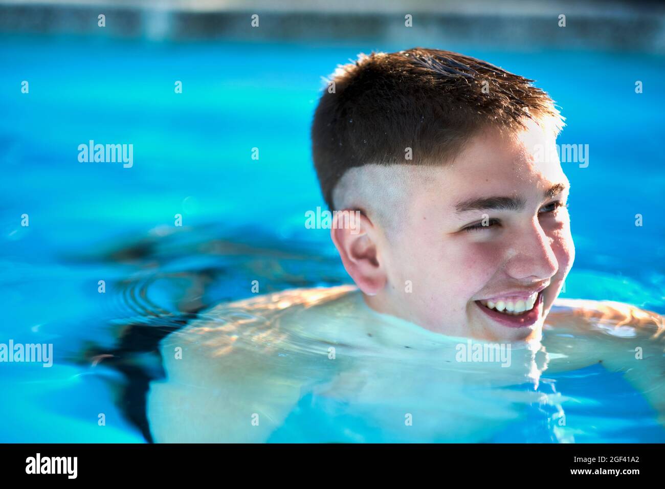 Portrait of a young caucasian boy inside a swimming pool, submerged in ...