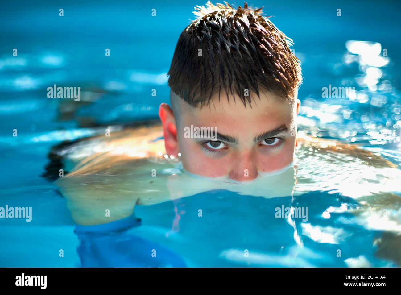 Portrait of a young caucasian boy inside a swimming pool, submerged in ...