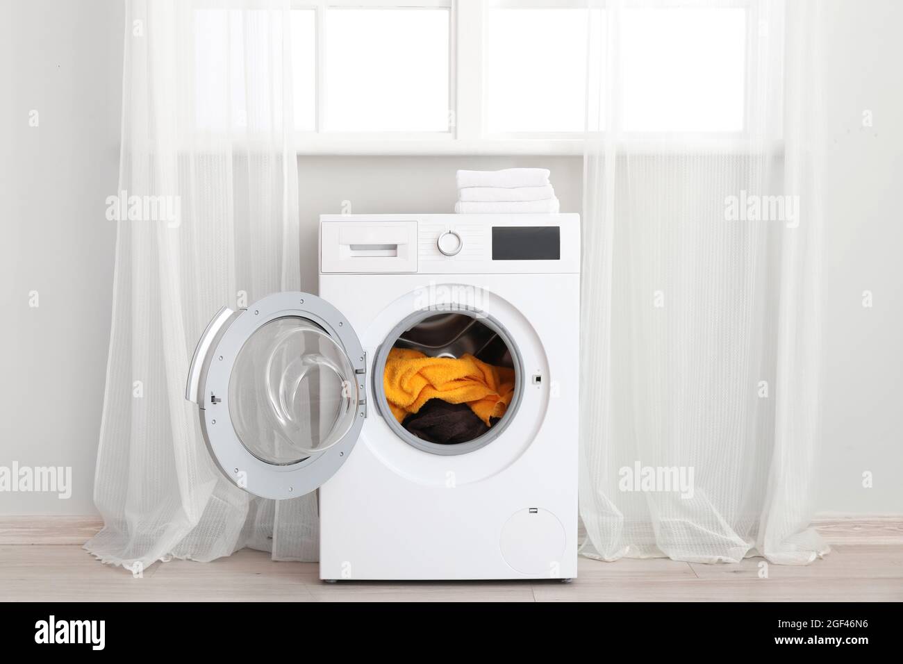 Modern washing machine with laundry near window Stock Photo - Alamy