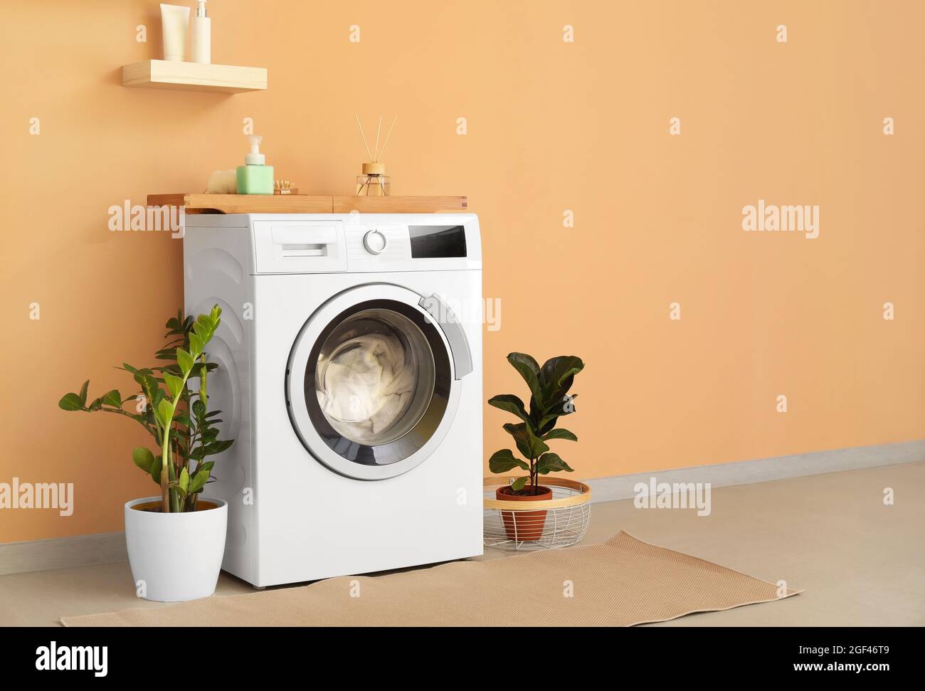 Modern washing machine with laundry near color wall Stock Photo - Alamy