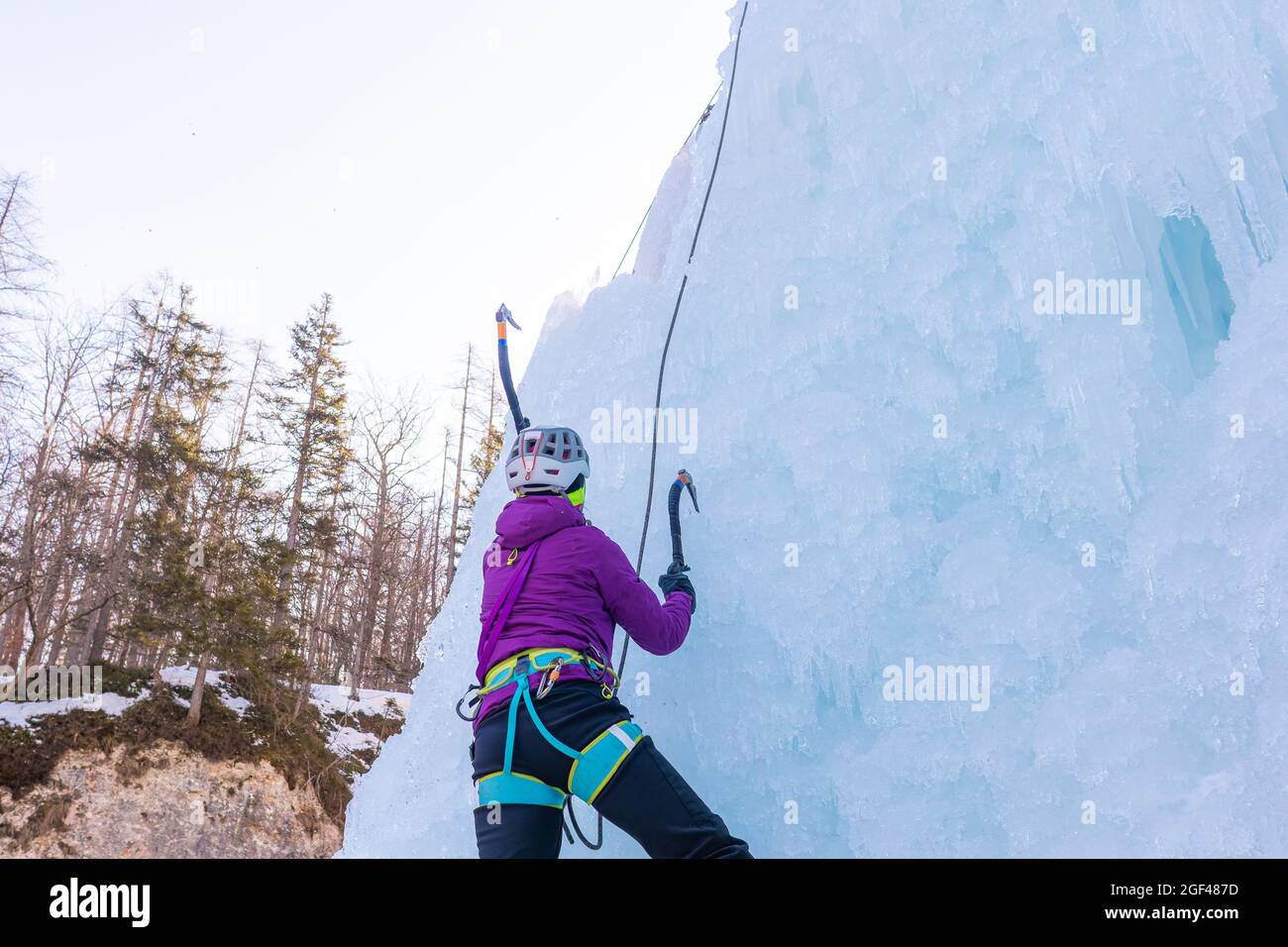 Female ice climber silhouette swinging axes into the ice with force ...