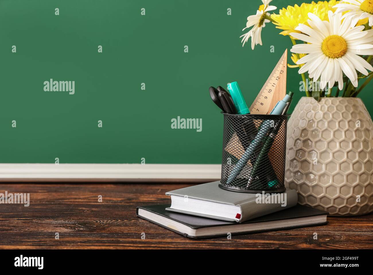 Vase with flowers and stationery on table in classroom. Teacher's Day ...