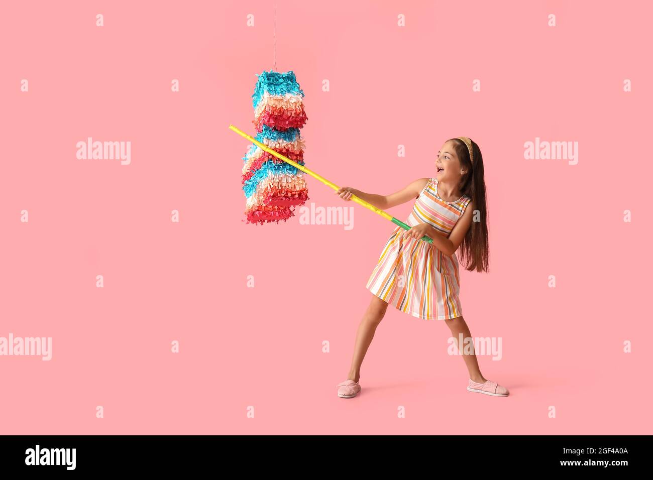 Little girl breaking Mexican pinata on color background Stock Photo - Alamy