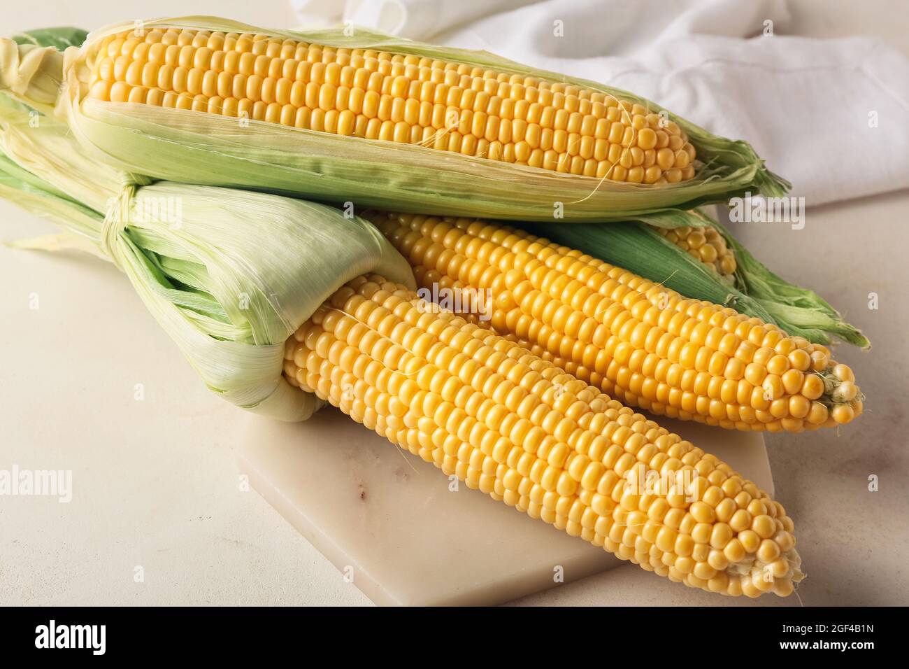 Board with fresh corn cobs on light background Stock Photo - Alamy