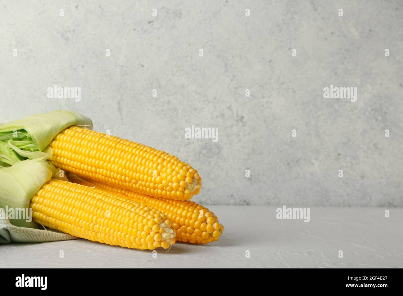 Fresh corn cobs on light background Stock Photo - Alamy