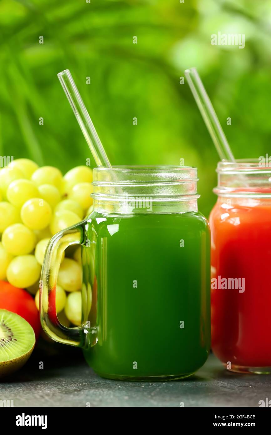Mason jars with healthy juice, fruits and vegetables on table outdoors ...