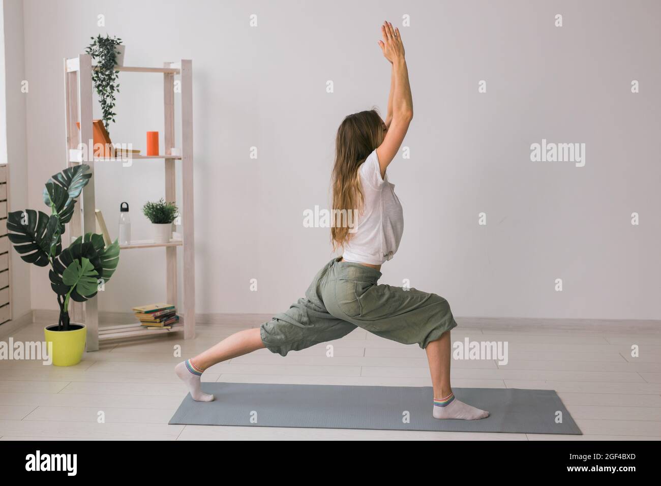 Woman practise yoga performs. Pose on mat inside of cozy room with ...